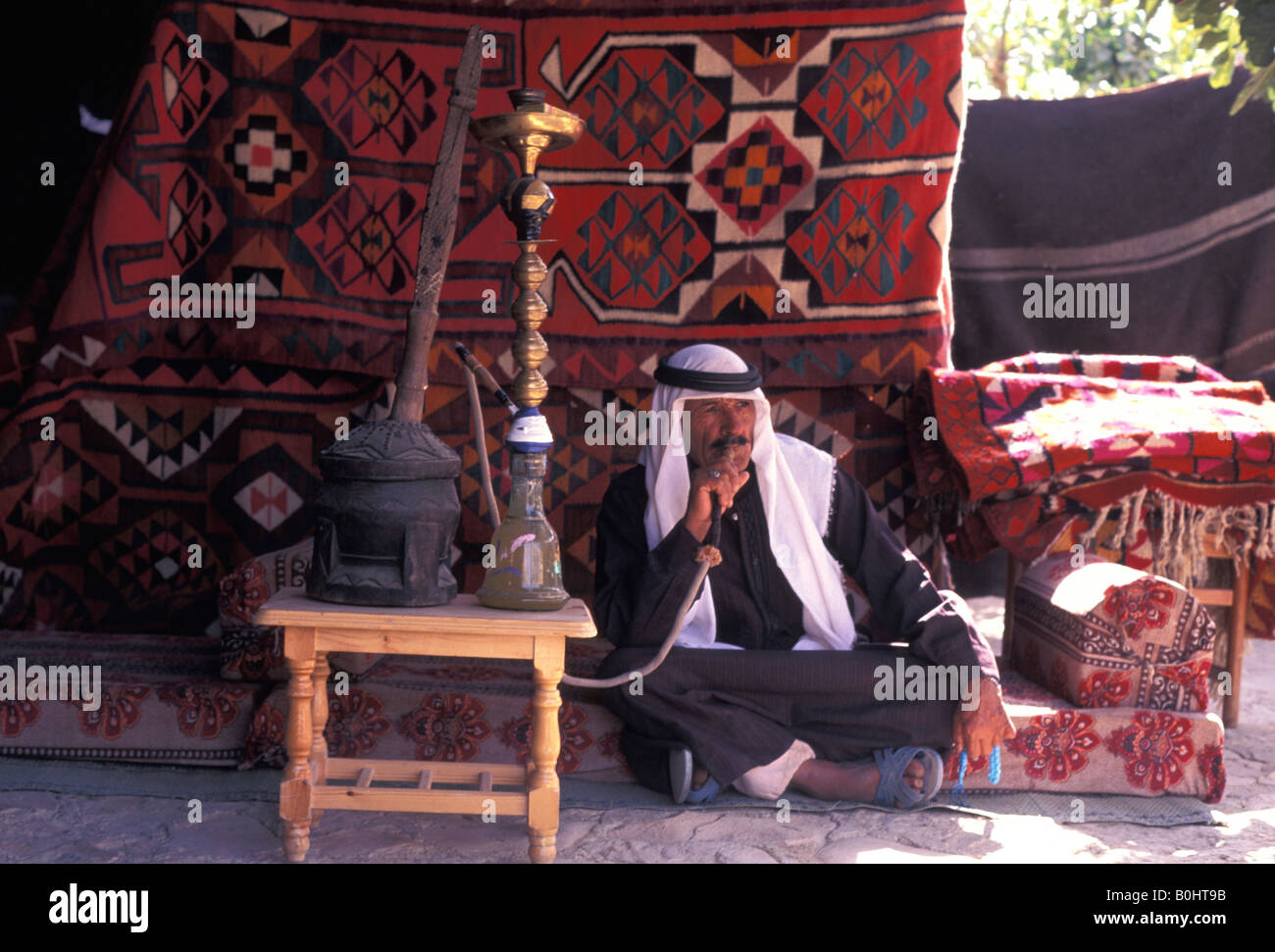 A man smoking a hookah outside his carpet stall, Jordan Stock Photo - Alamy