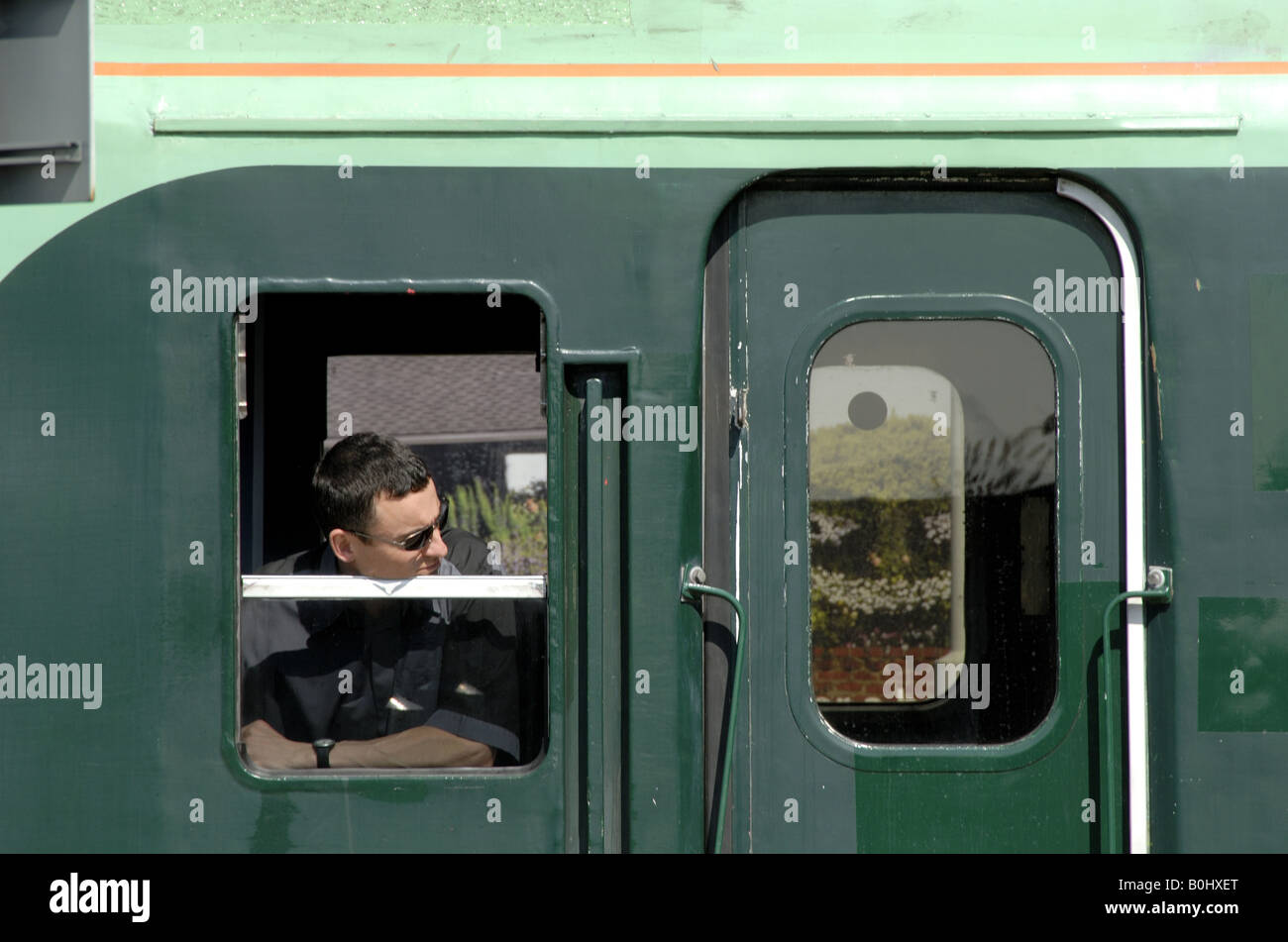 A train driver leans out the window of the train while stopped on the ...