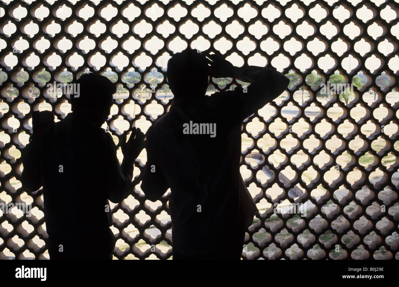Two visitors looking through a window frame at the Red Fort, Agra IN ...