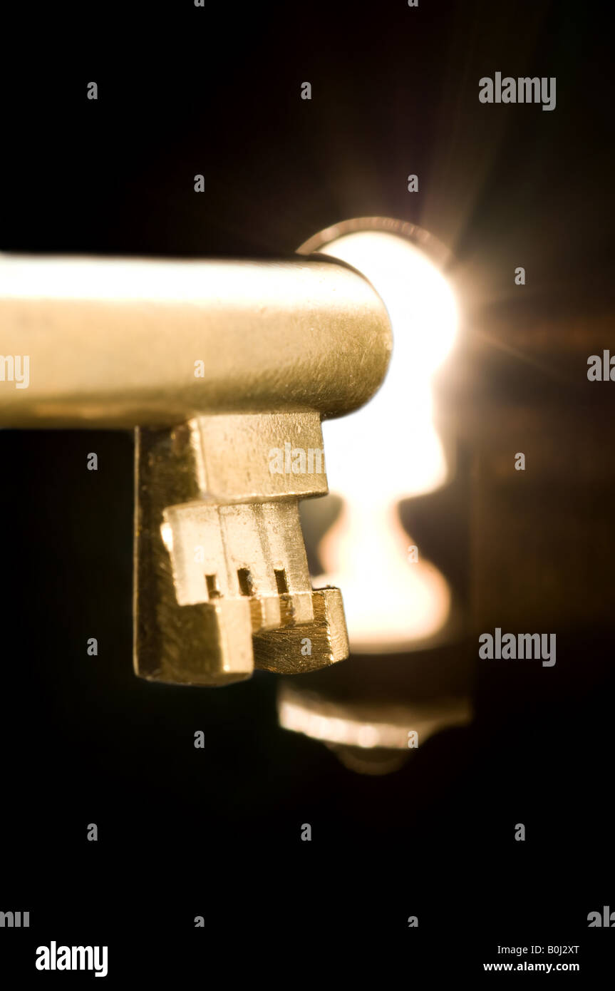 A golden key in a keyhole illuminated by a mysterious radiant light ...