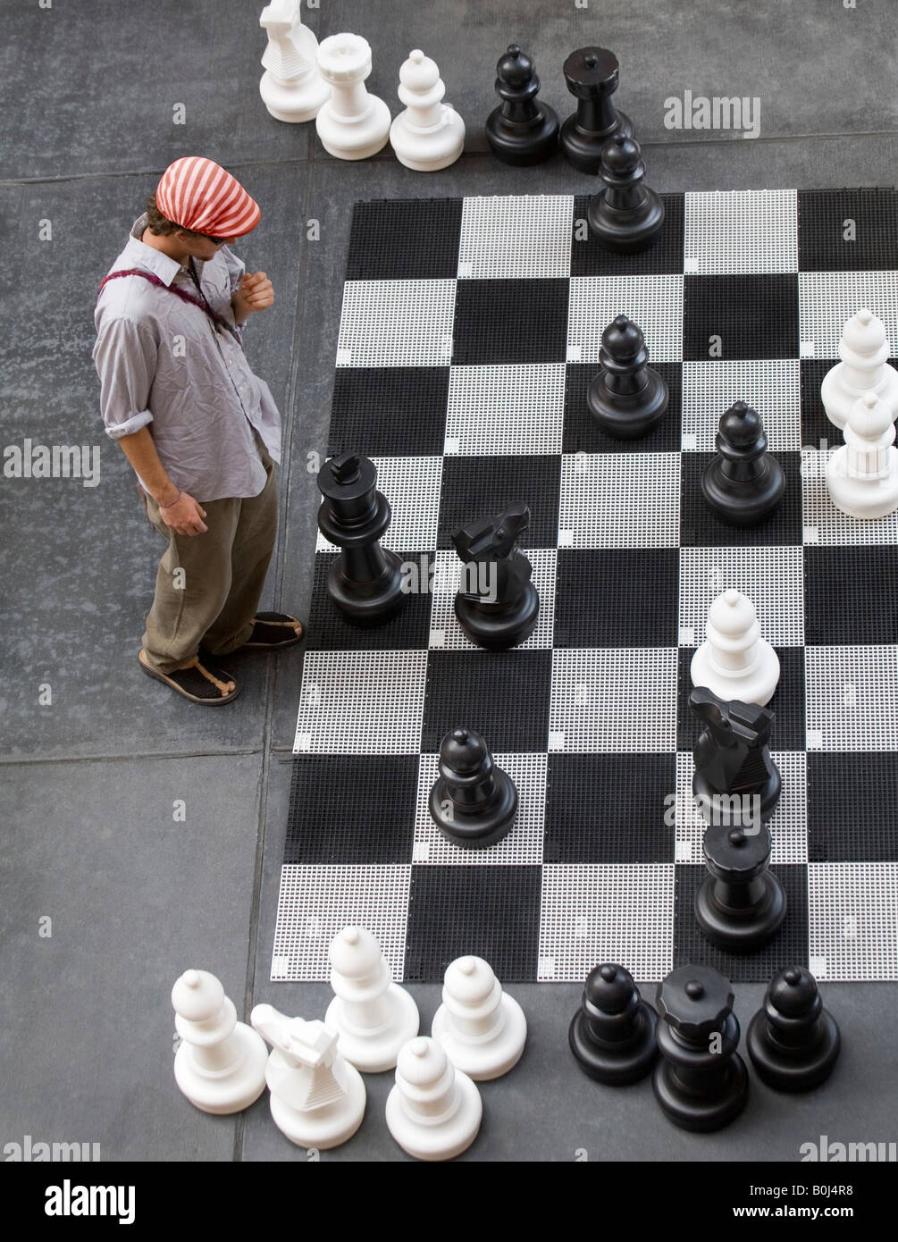 Looking down on a young man playing chess on a life-sized chessboard ...
