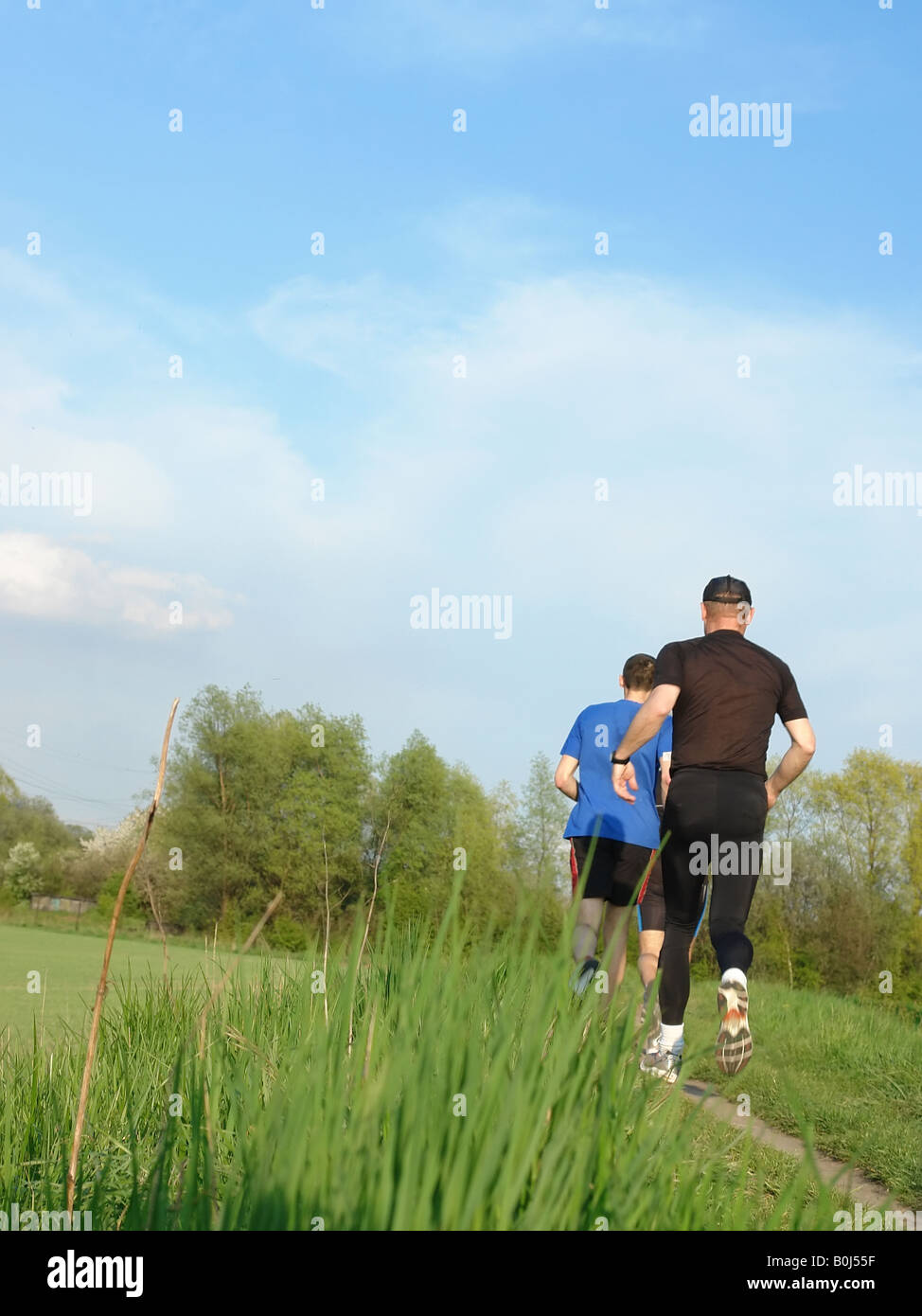Men jogging along field path Stock Photo - Alamy