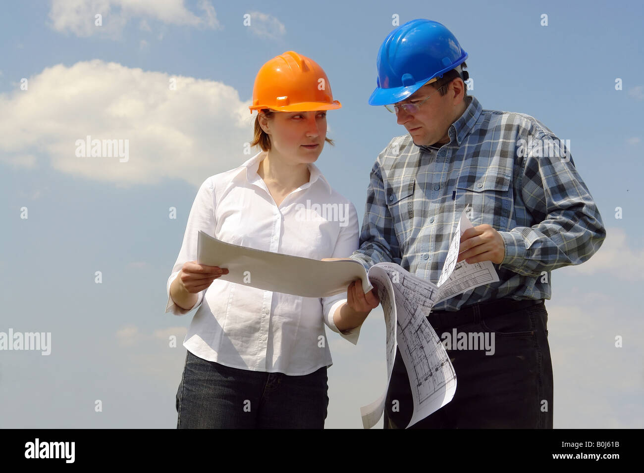 Female investor and site manager discussing building plans over blue ...