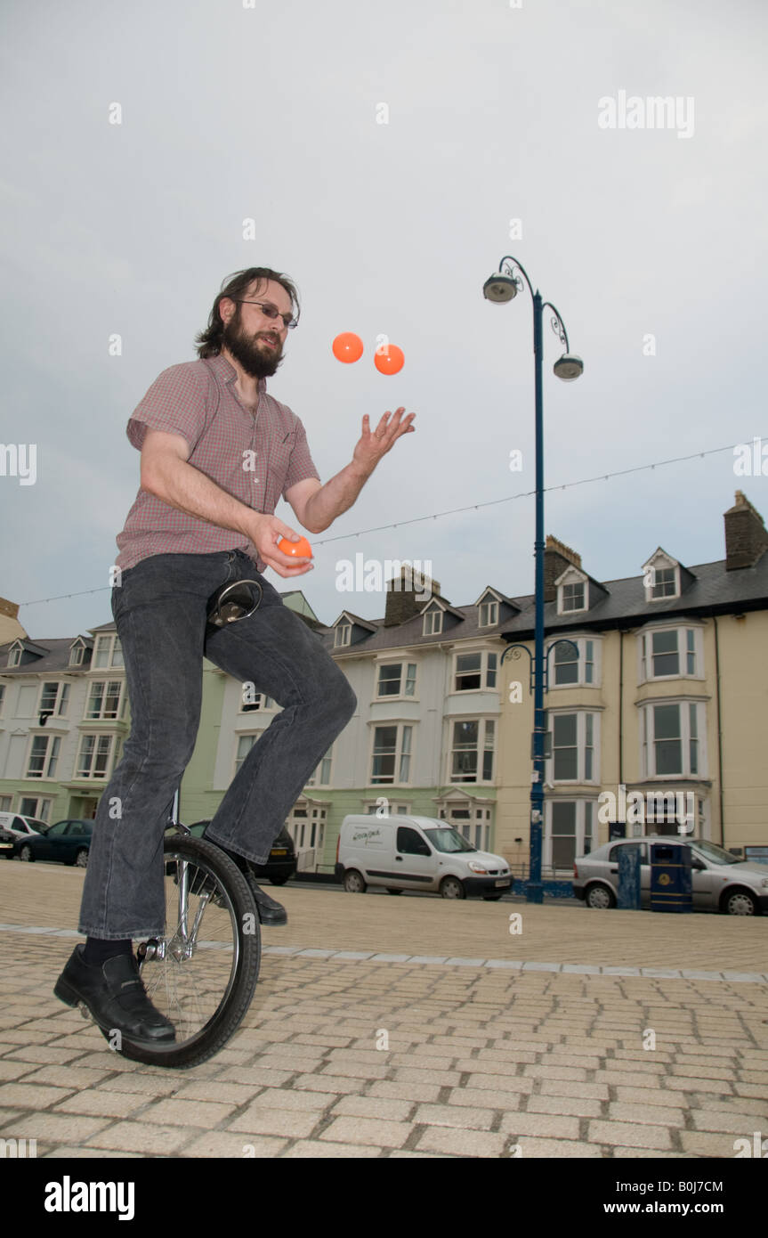 man on unicycle juggling three orange balls on Aberystwyth promenade ...