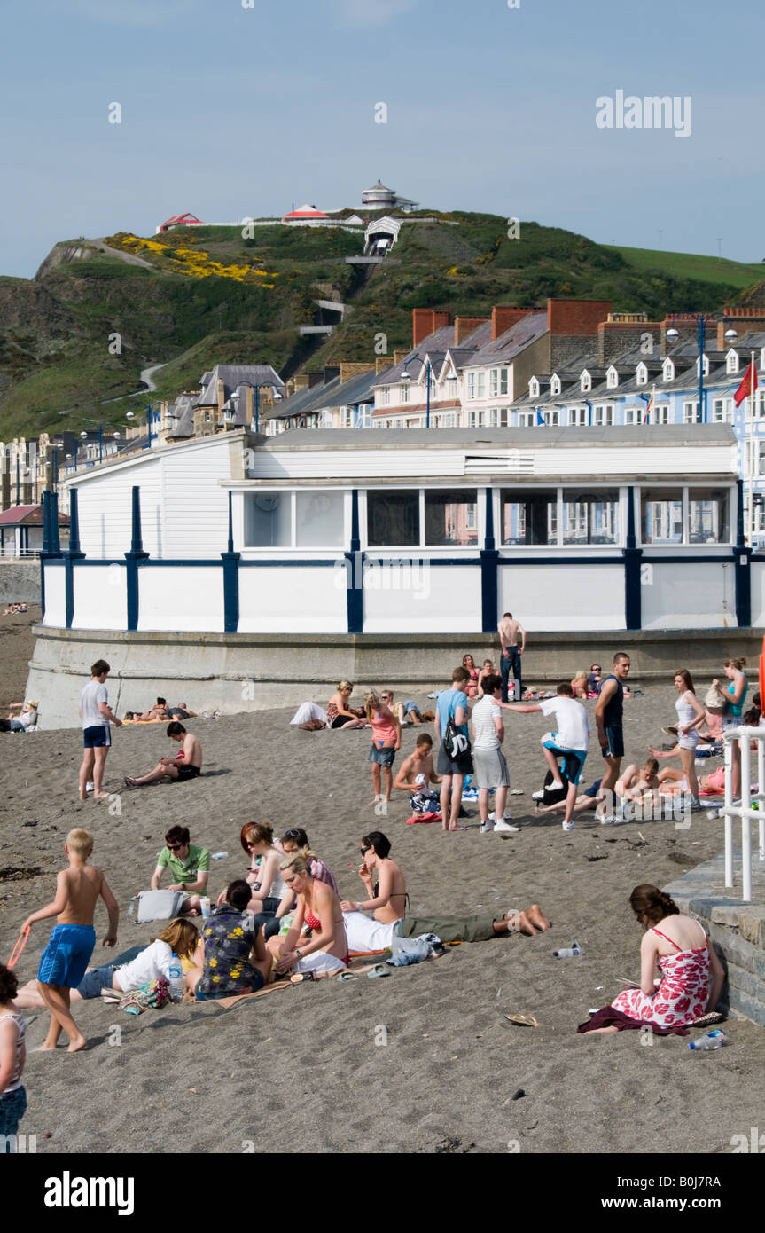 people sunbathing and sitting on Aberystwyth beach seaside promenade ...