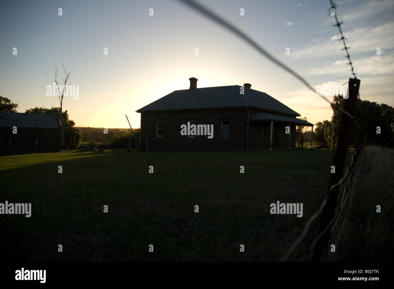 Dramatic semi silhouette heritage blue-stone farm at dusk with fence ...