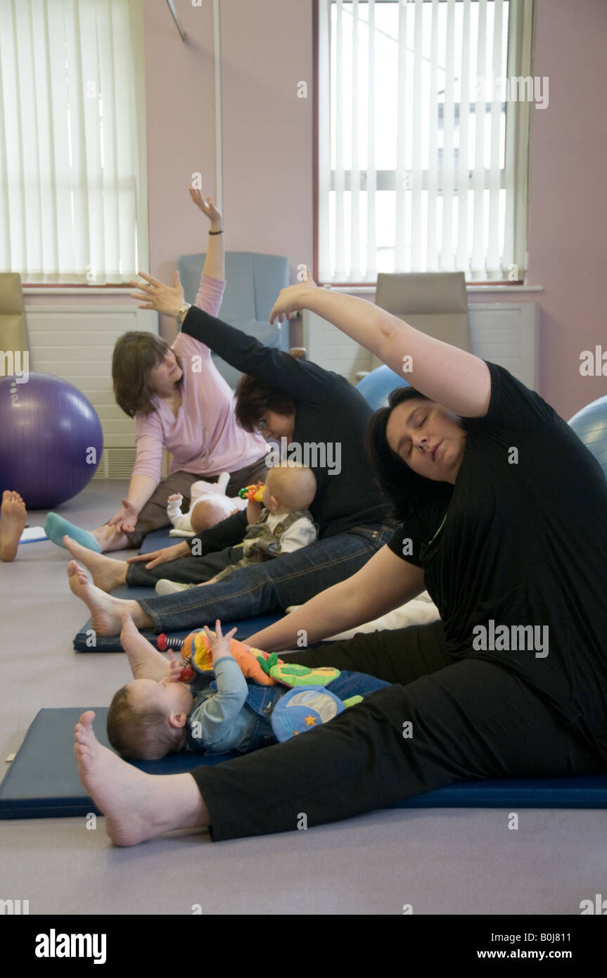 New mother with her young baby at doing stretching exercise a post ...