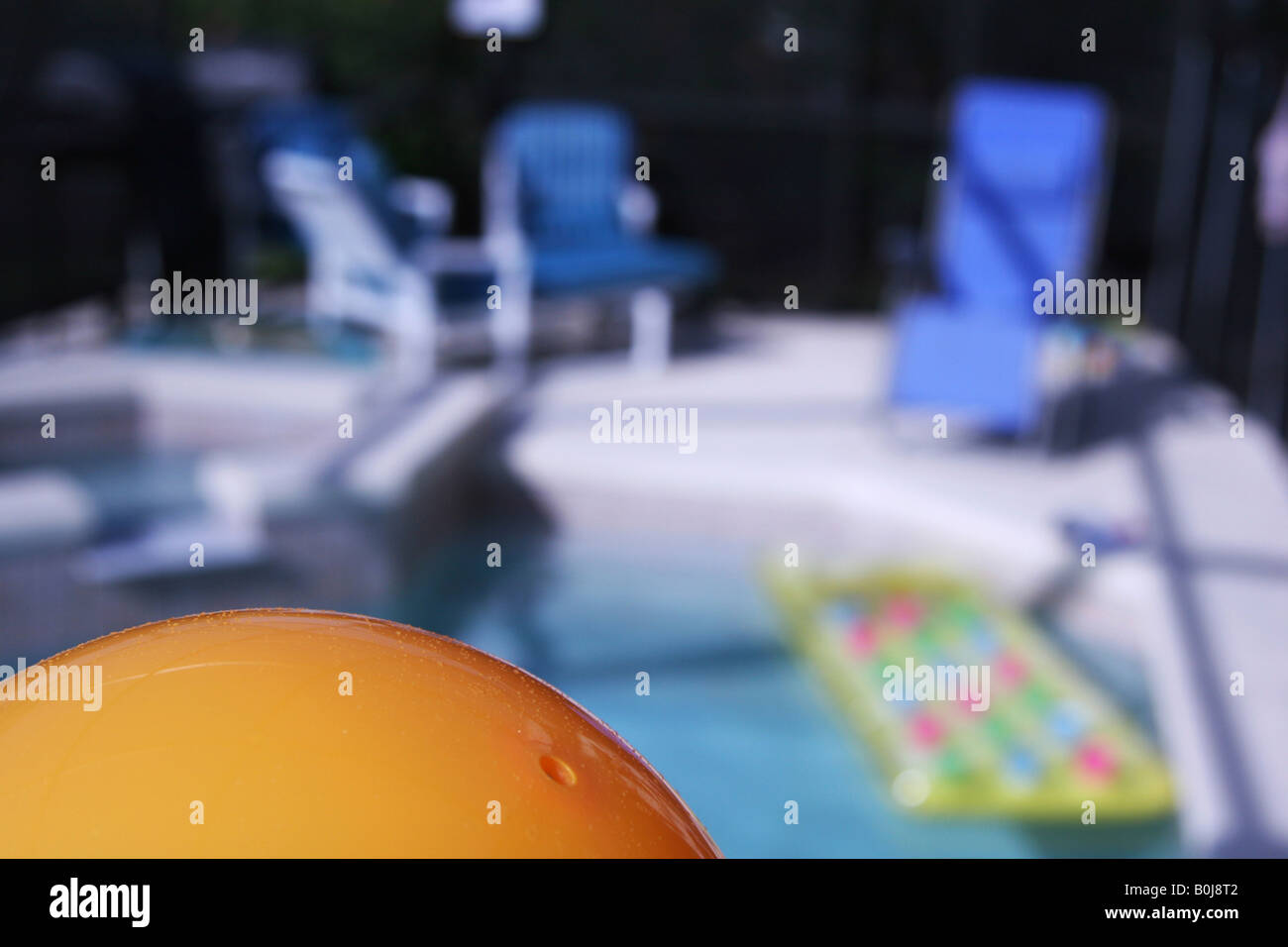 abstract photo of a private pool focus is on pool ball and deck chairs ...