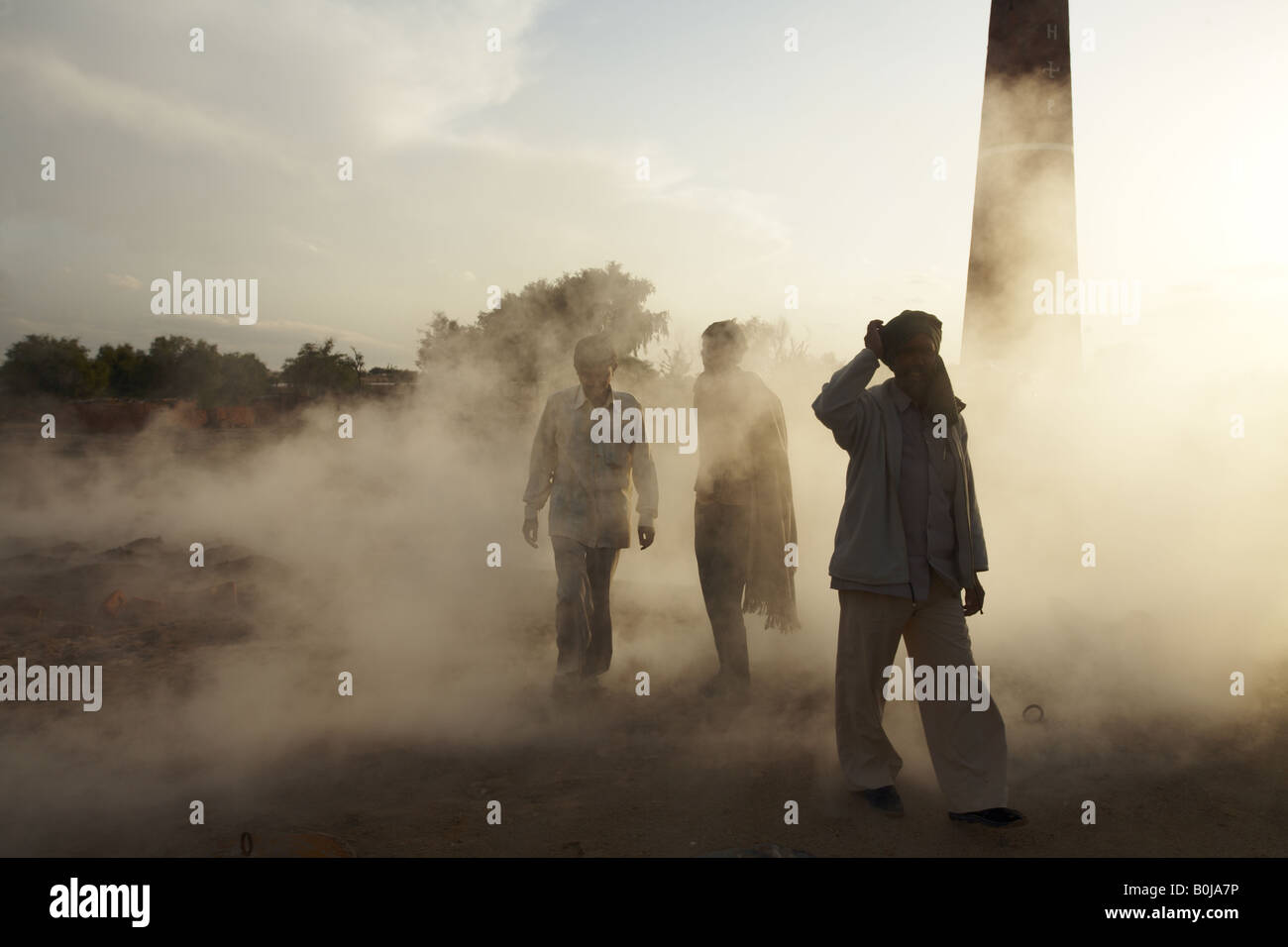 Men walking through the smoke from a brickworks in Rajasthan India ...