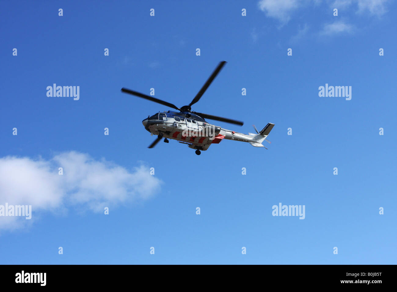 big helicopter flying overhead blue sky with stray clouds Stock Photo ...
