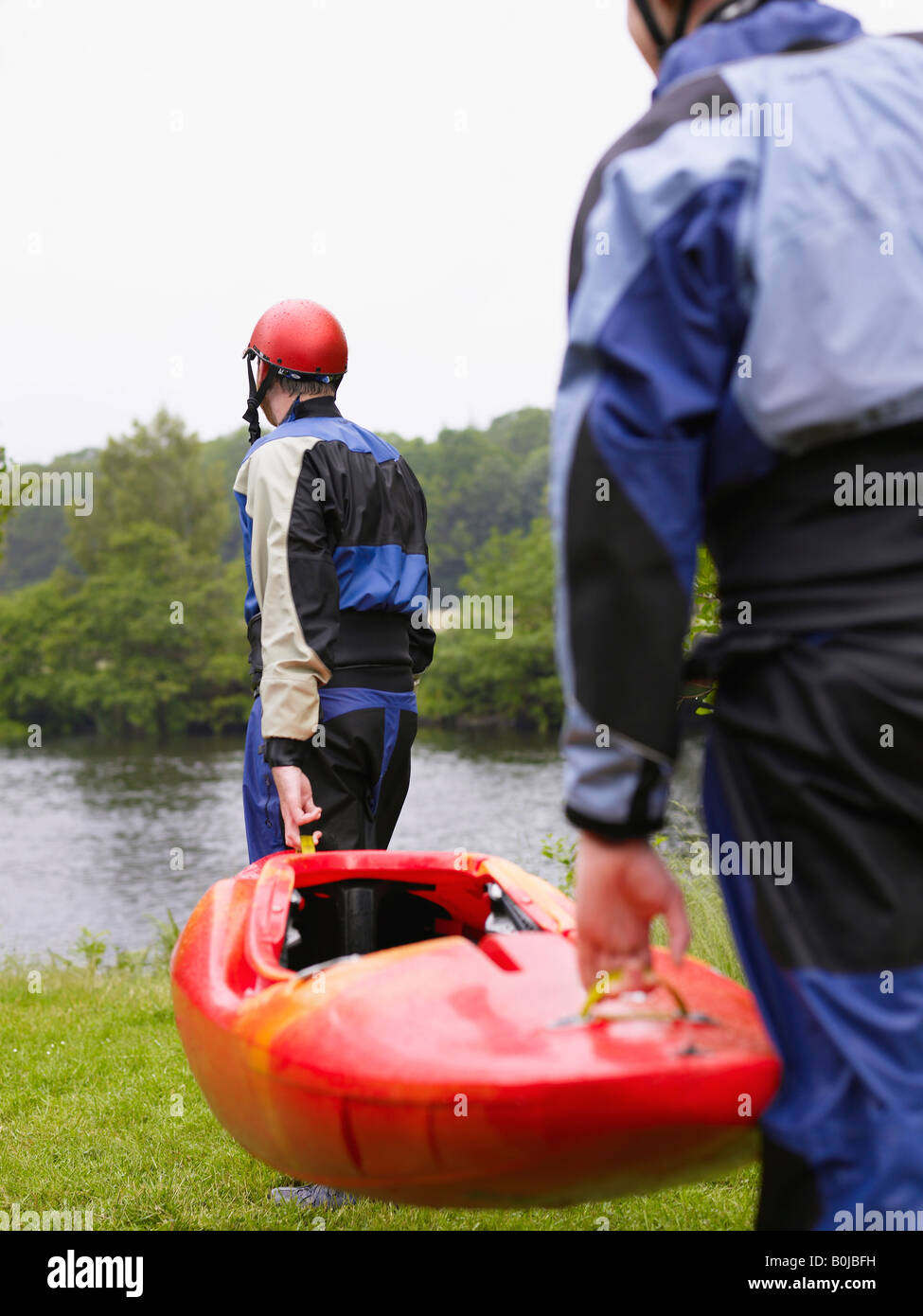 Two men carrying kayak to river Stock Photo - Alamy