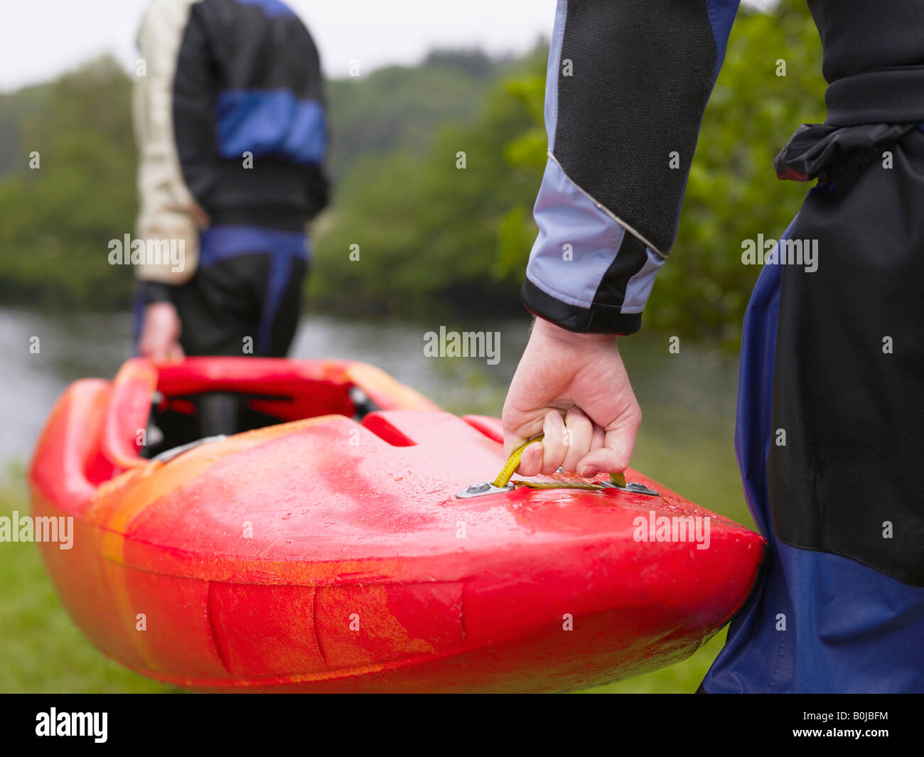 Two men carrying kayak to river Stock Photo - Alamy