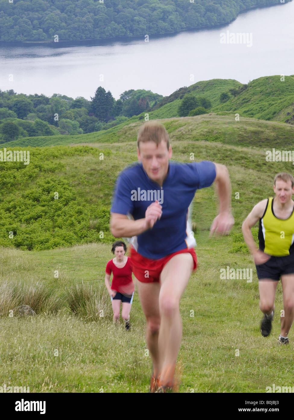 Three people running up hillside Stock Photo - Alamy