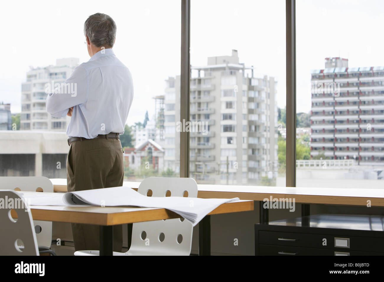 Business man looking out of office window, back view Stock Photo - Alamy