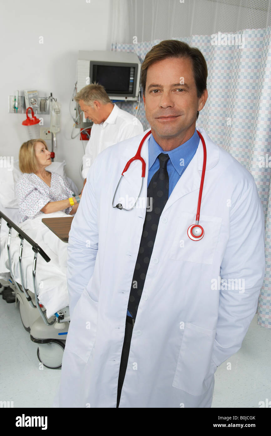 Portrait of doctor in hospital room, patient in background Stock Photo ...