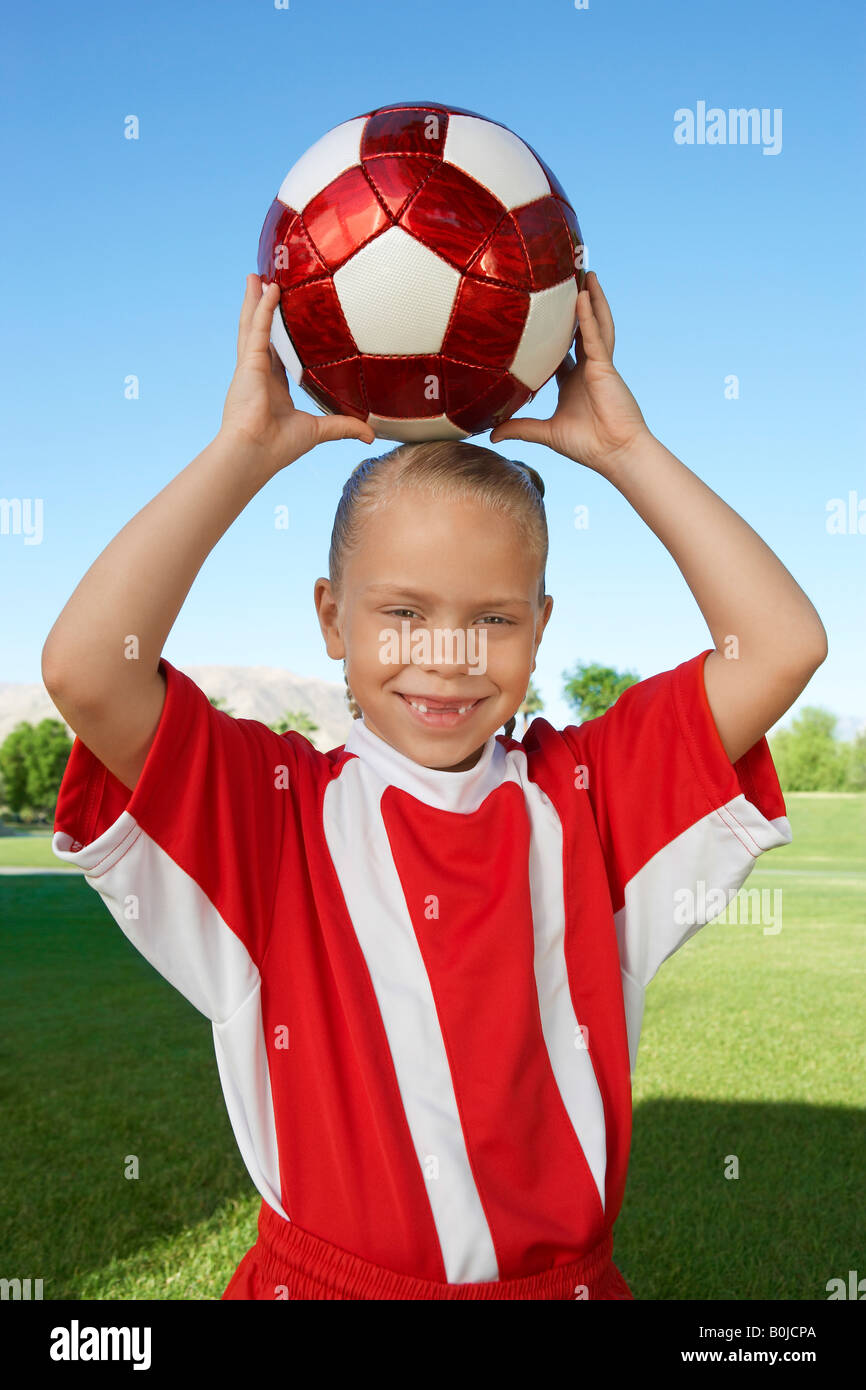 Girl (7-9 years) soccer player holding ball above head, portrait Stock ...
