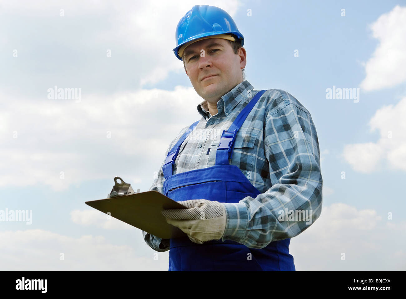 Construction site manager wearing blue helmet and overall with notepad ...