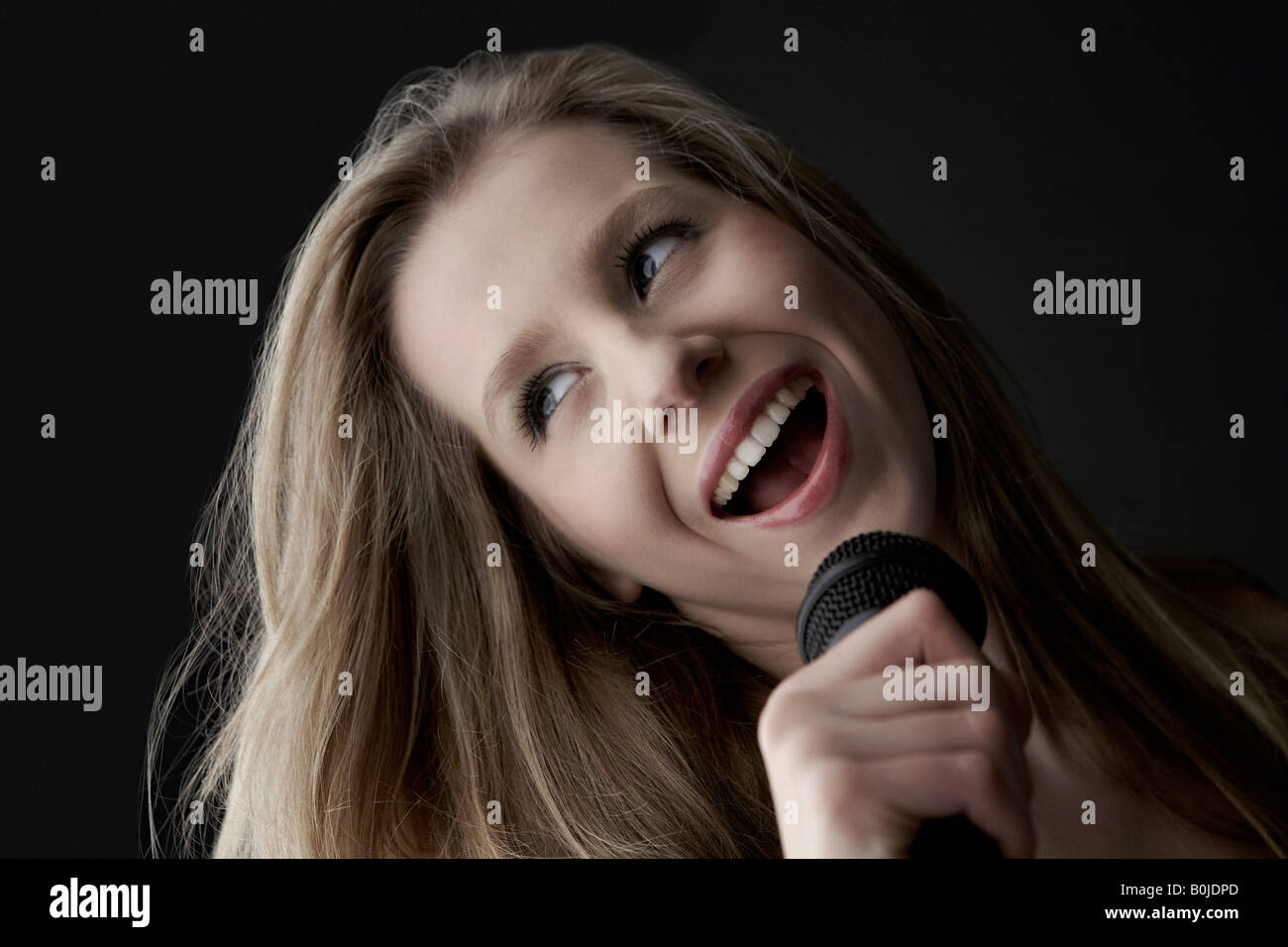 Young woman singing into microphone, close-up Stock Photo - Alamy