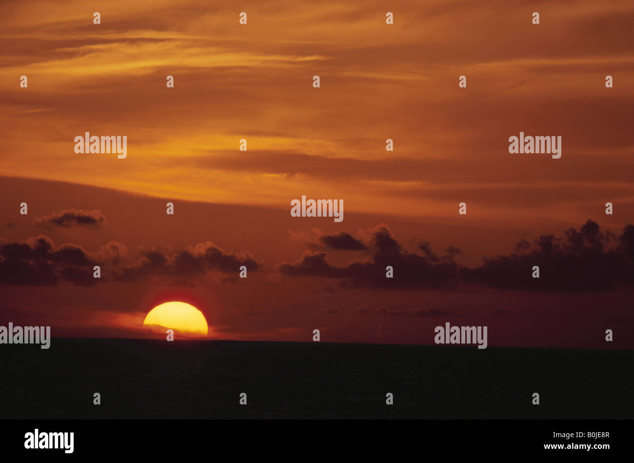 The Setting Sun On The Beach Stock Photo - Alamy