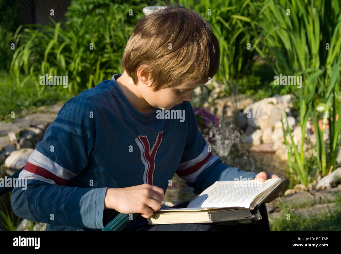 Boy reading a book outside in the garden Stock Photo - Alamy