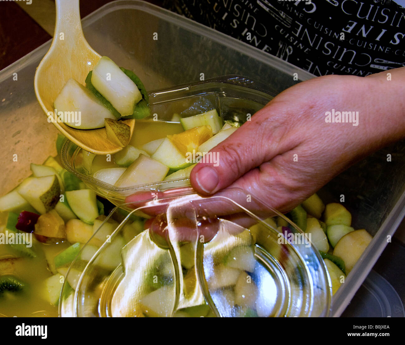 Food preparation - Fruit salad being spooned into a clear plastic ...