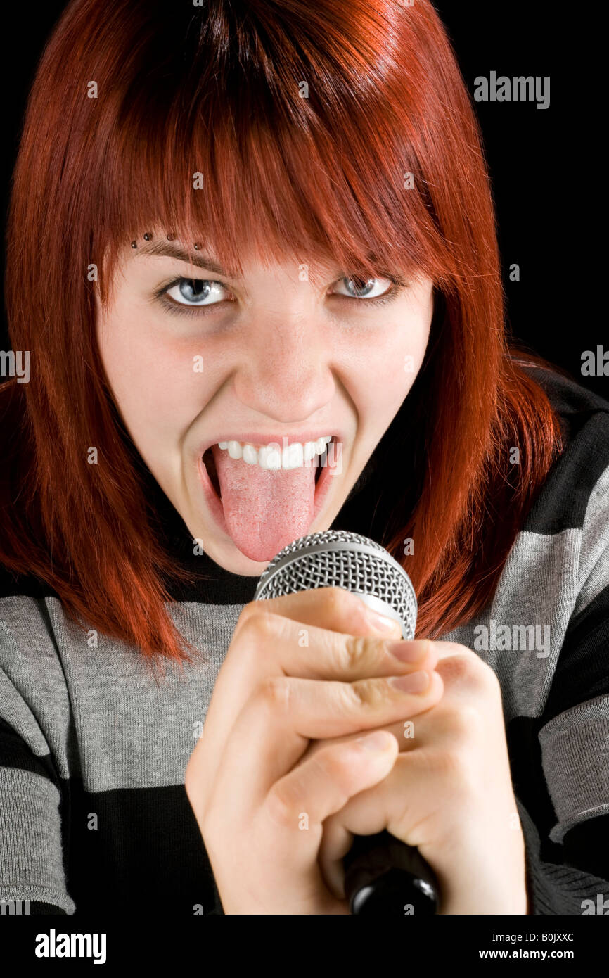 A happy redhead girl holding a karaoke microphone and screaming Studio ...
