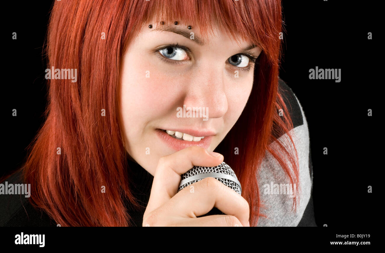 Cute smiling redhead girl singing on microphone Studio shot Stock Photo ...