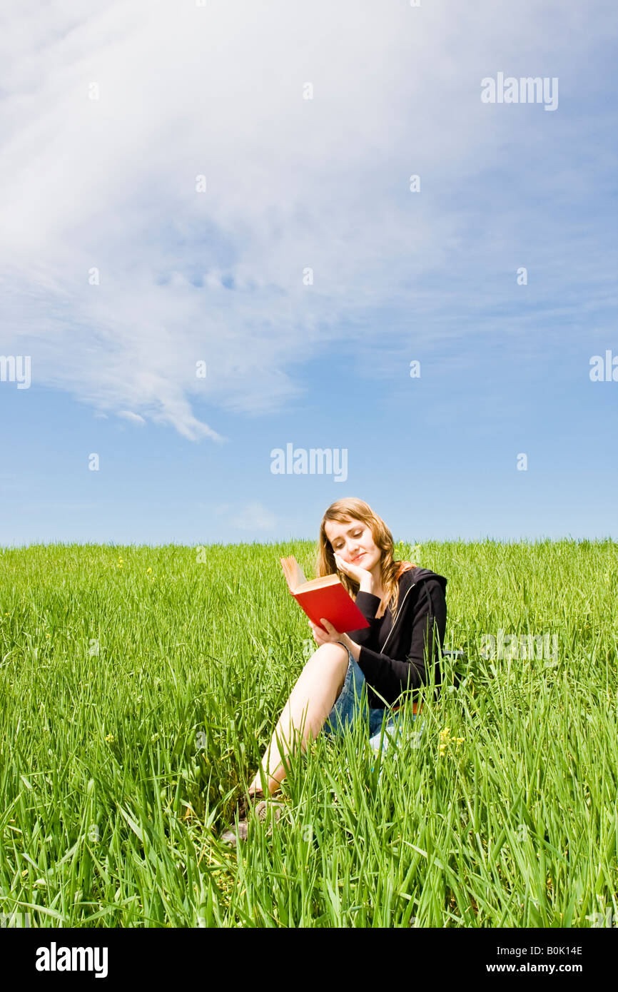 Blond woman reading over the grass Stock Photo - Alamy