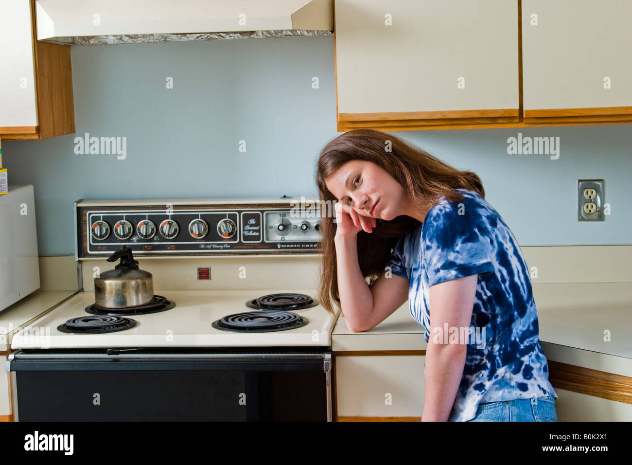 Young woman leaning on the counter in her kitchen MODEL RELEASED Stock ...