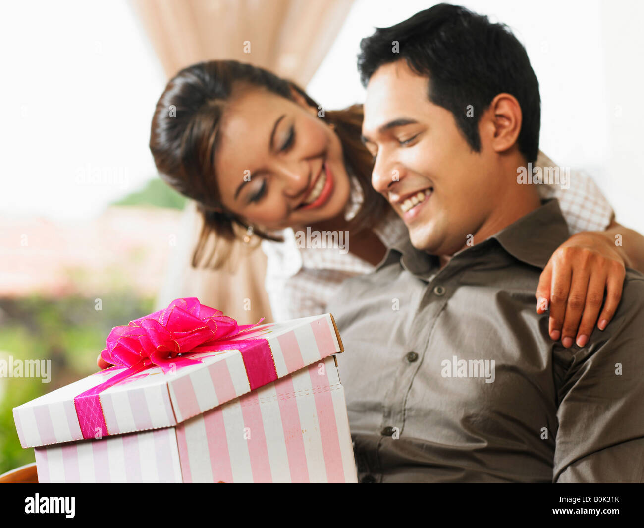 man receiving a surprise gift from woman Stock Photo - Alamy
