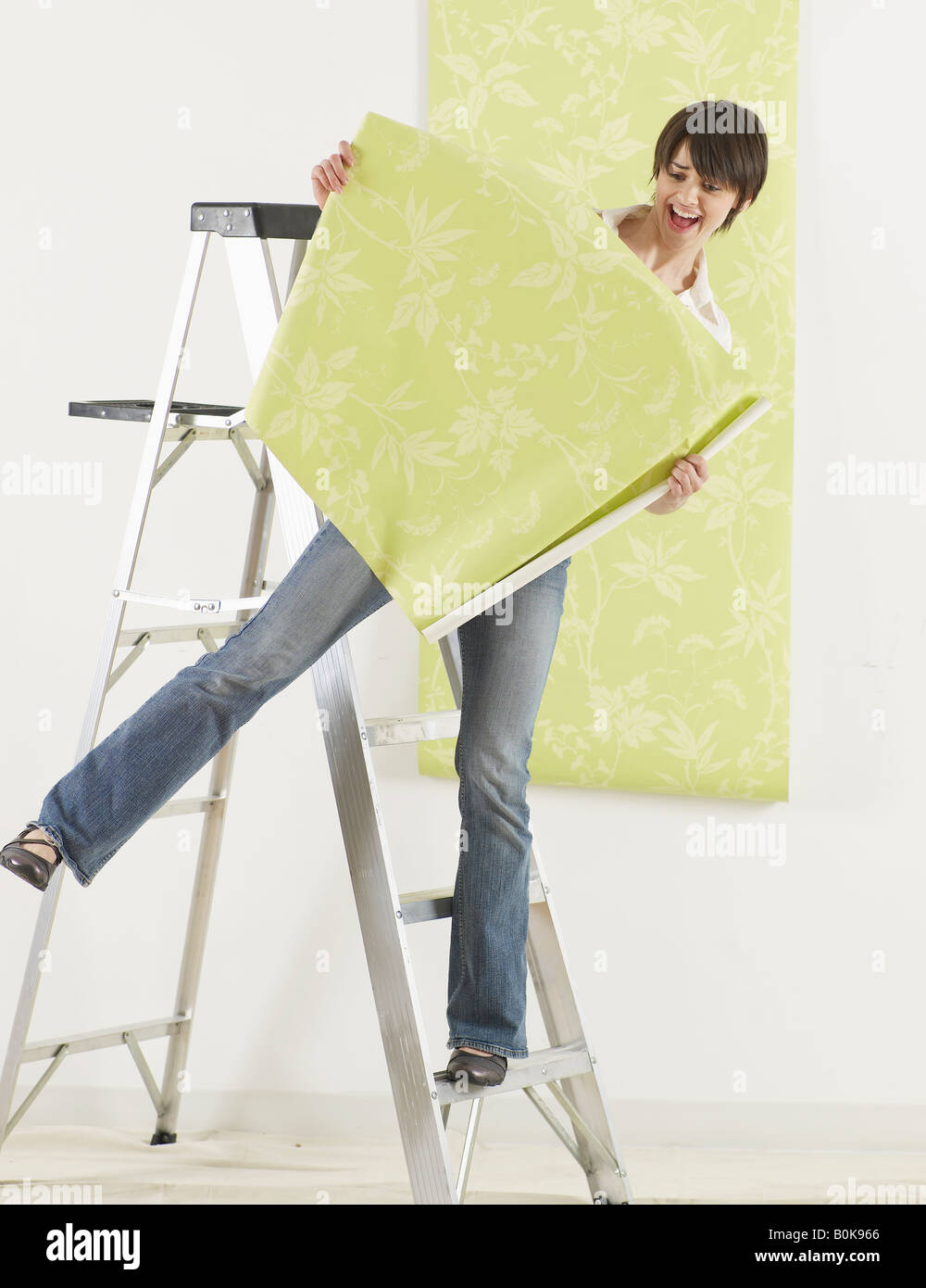Young Woman Balancing on Stepladder and Holding Wallpaper Stock Photo ...