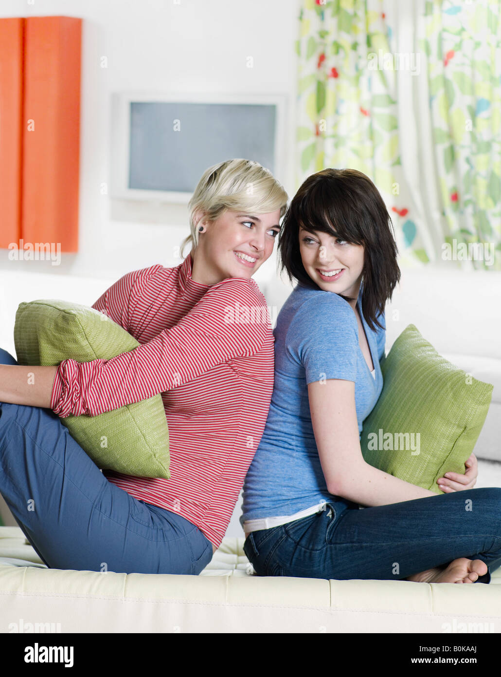 Two Young Women Sitting Back to Back Stock Photo - Alamy