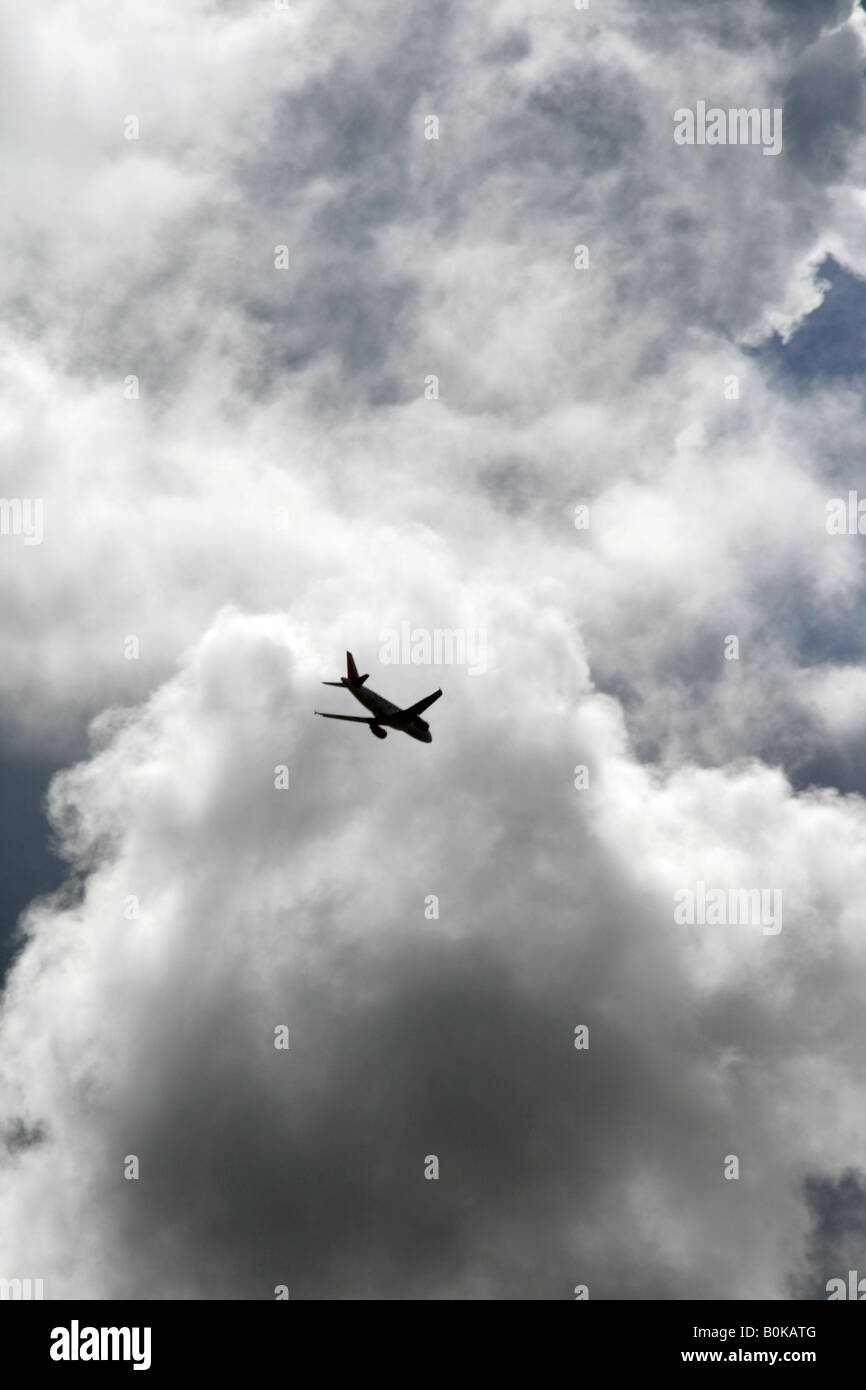 plane flying through dark clouds in sky Stock Photo - Alamy