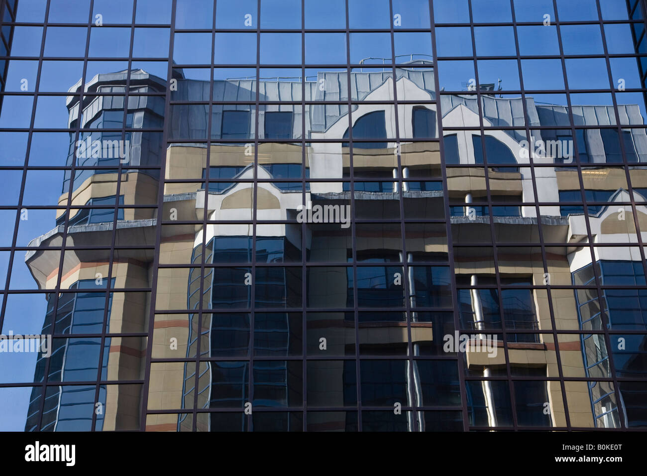 Reflection of modern building in the glass panelled windows of another ...
