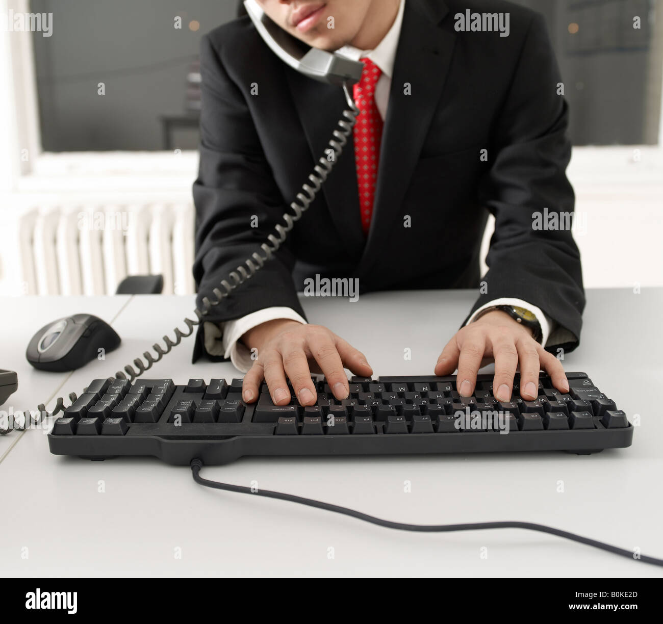 Office Worker Typing with Keyboard While on Phone Stock Photo - Alamy