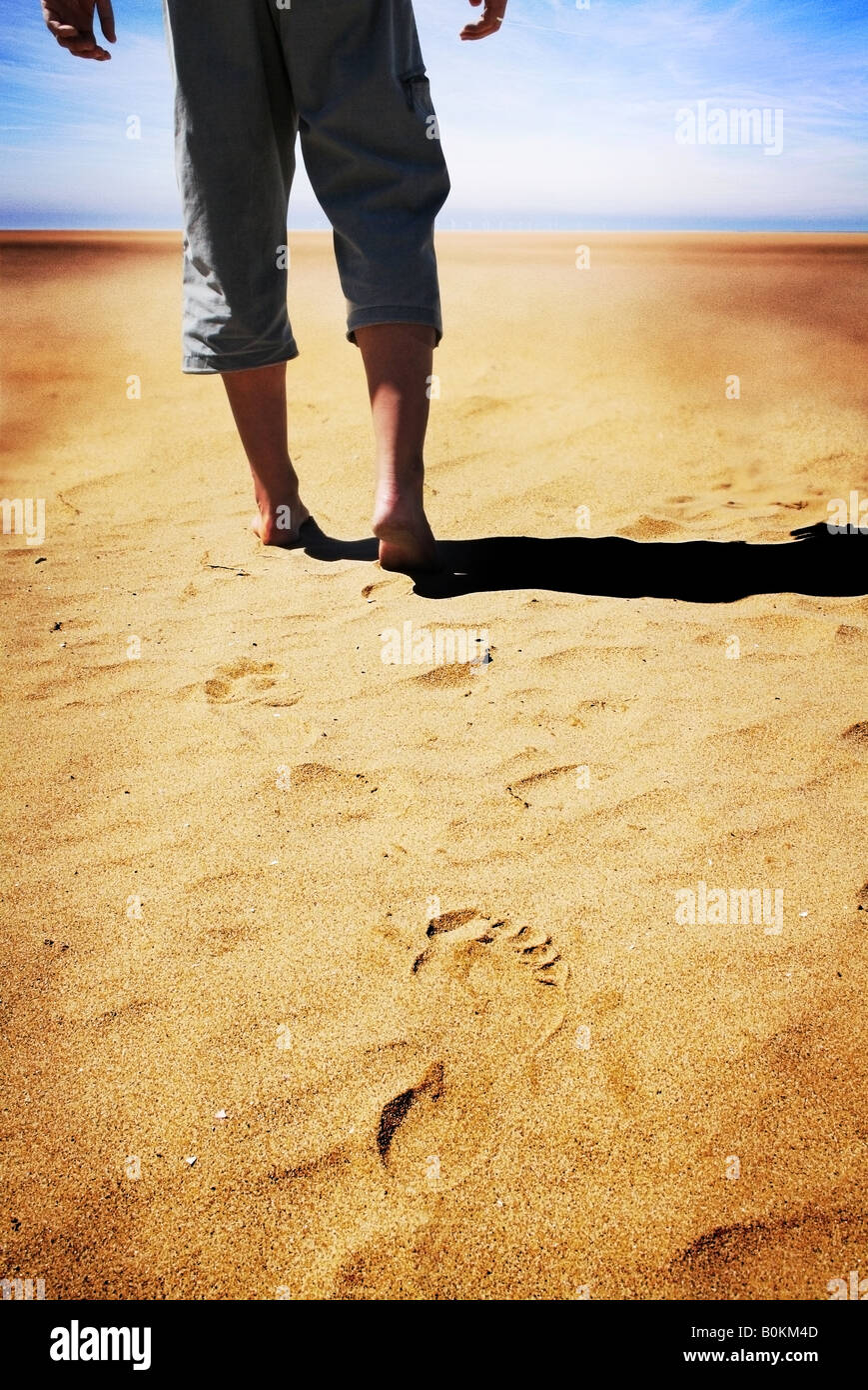 man walking bare foot alone on sand with clear footprint left in soft ...