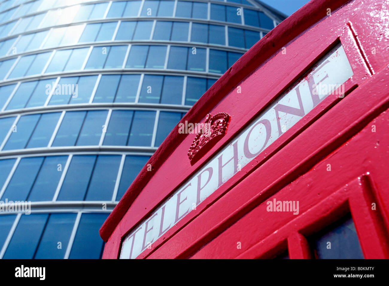 A traditional red telephone box with modern glass office building in ...
