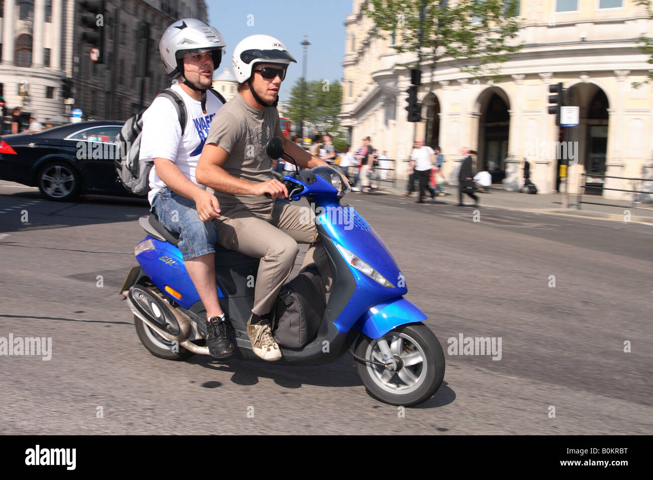 London motor scooter motorbike with pillion passenger commuter traffic driving around Trafalgar ...