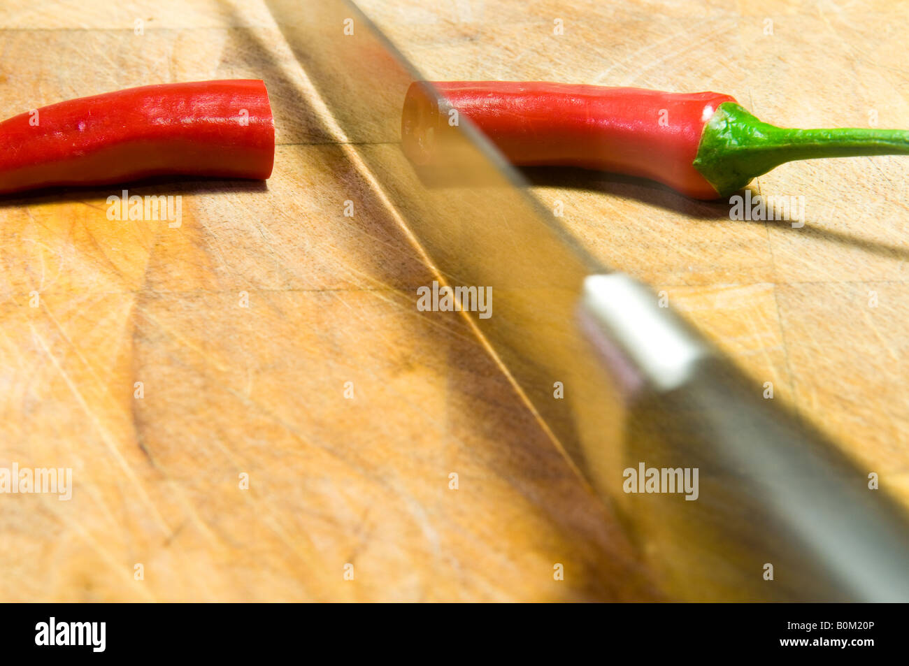 A single red chilli seen being chopped on a chopping block Stock Photo ...