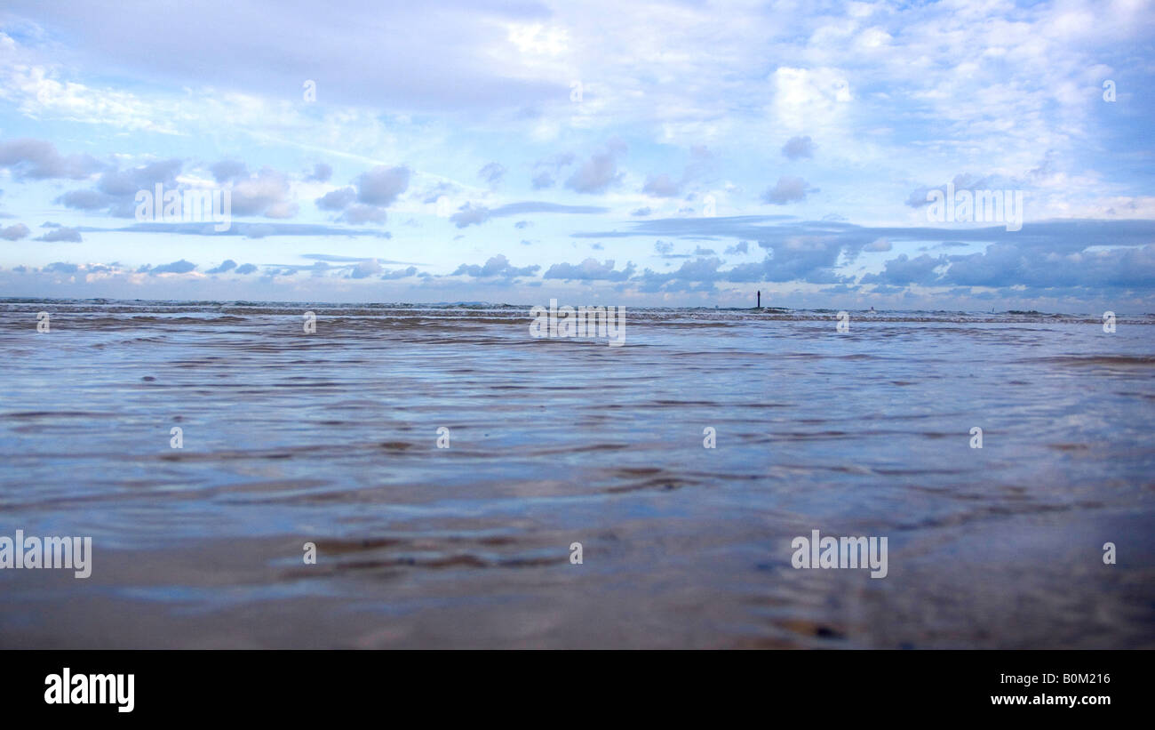 bright blue sky at the coast with tide coming in Stock Photo - Alamy