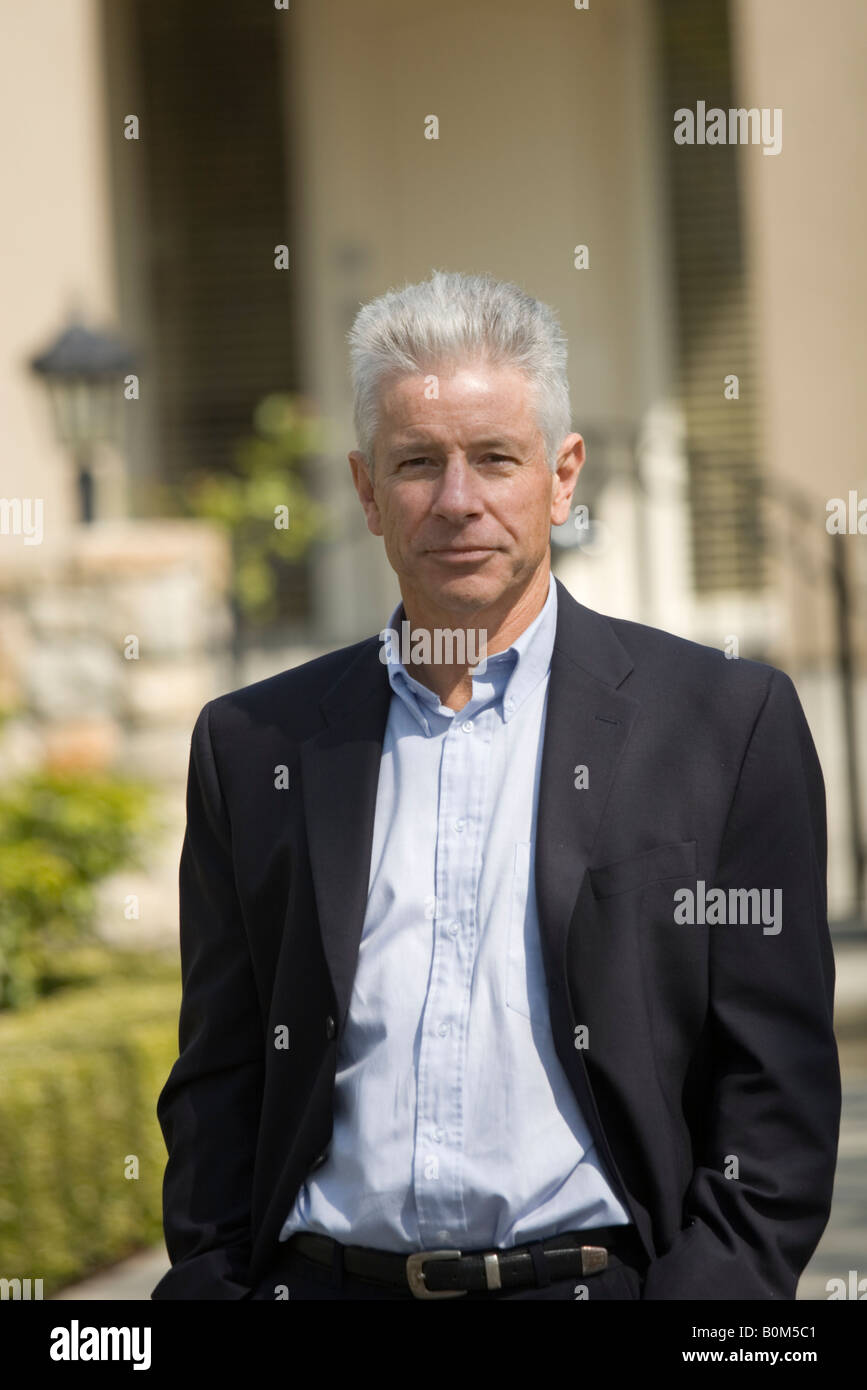 Male realtor standing outside in front of home for sale Stock Photo - Alamy