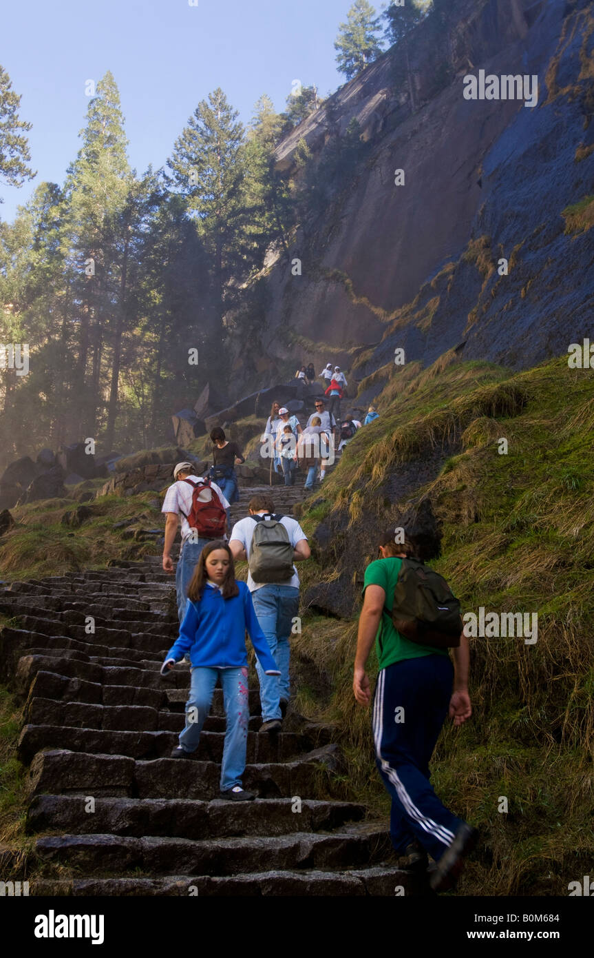 Hikers climbing on the steep rocky staircase stairs of the Mist Trail ...