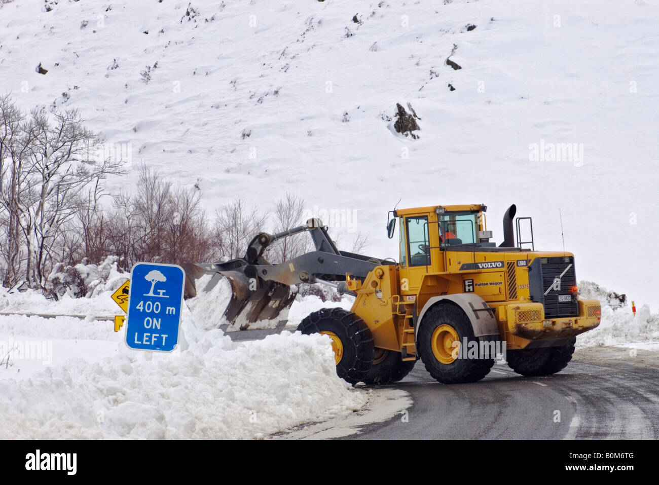 A front end loader clears road after heavy snow in the high country of ...