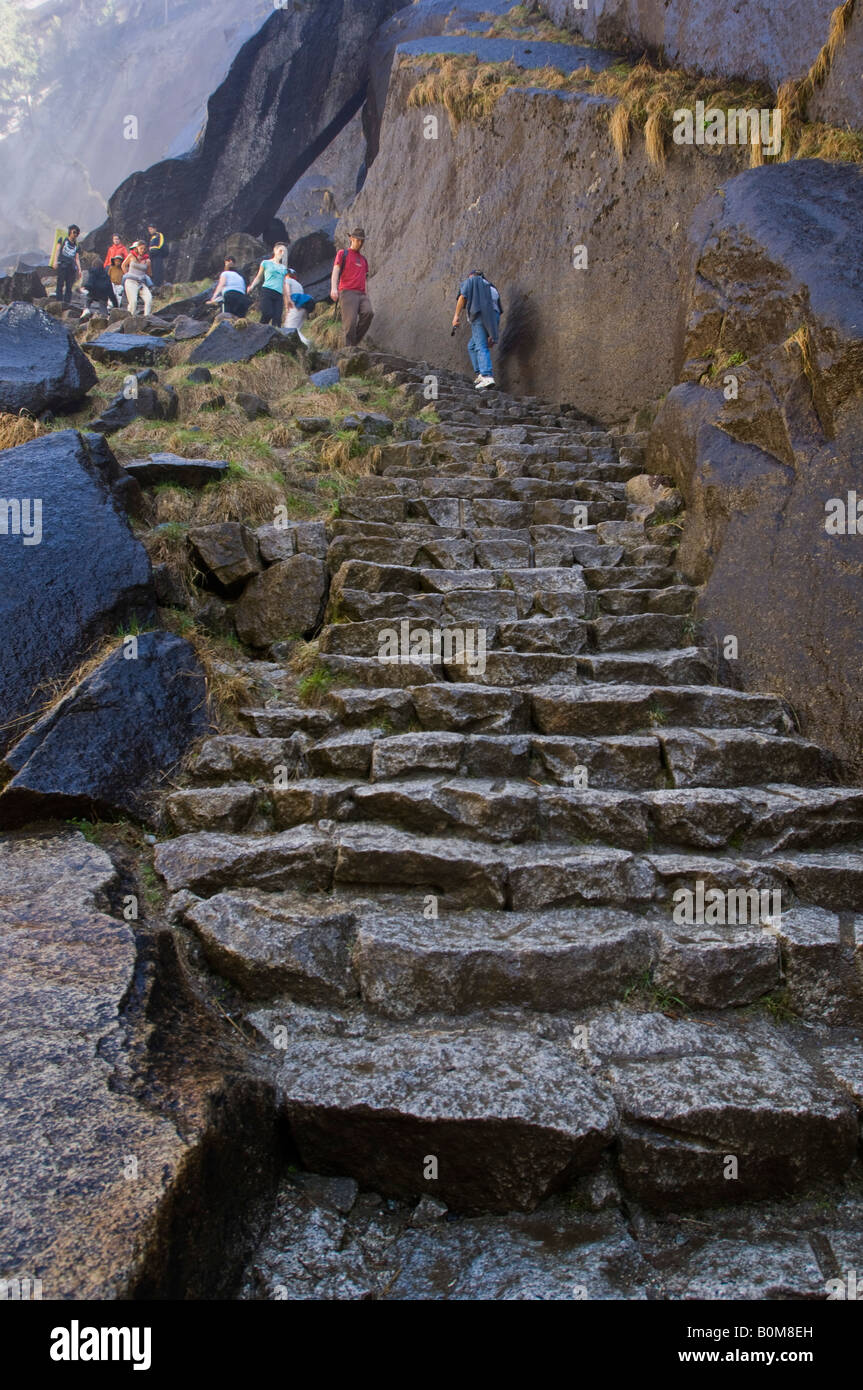 Hikers climbing on the steep rocky staircase stairs of the Mist Trail ...