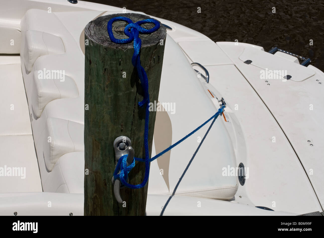 White boat tied to wooden piling by a thin blue rope Stock Photo - Alamy