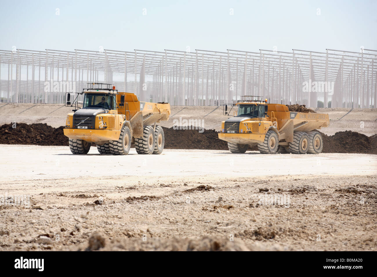 Large earth moving trucks on building site Stock Photo - Alamy