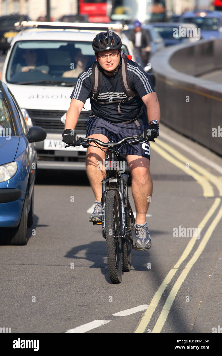 Cyclist riding through the busy traffic streets of Westminster London ...