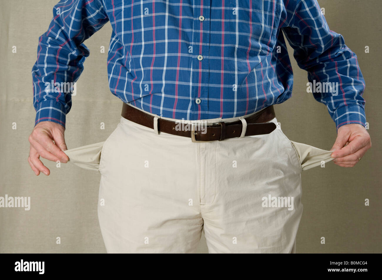 A man pulling out his trousers pockets to show that he has no money ...