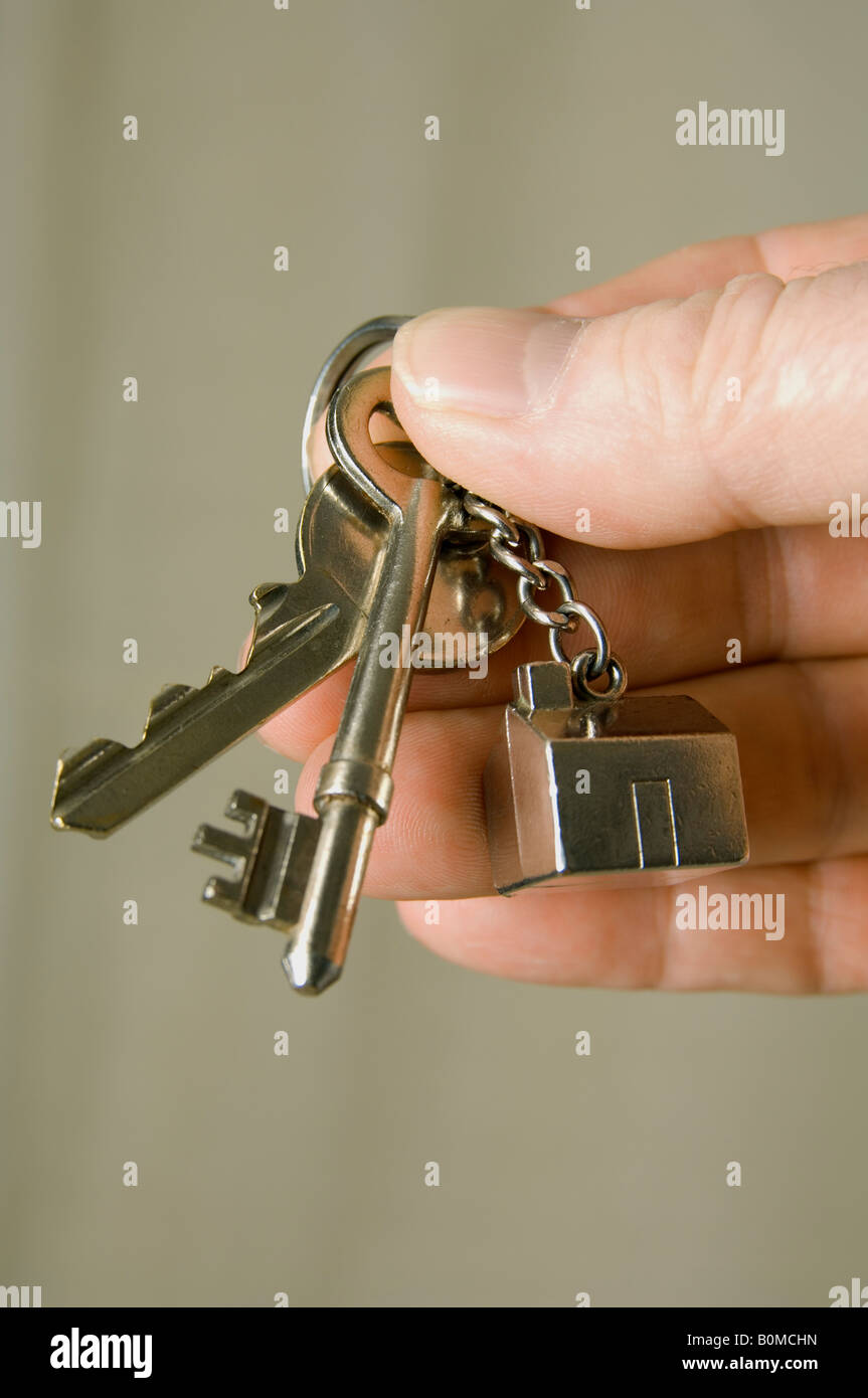 A man's hand holding house keys with a house fob Stock Photo - Alamy