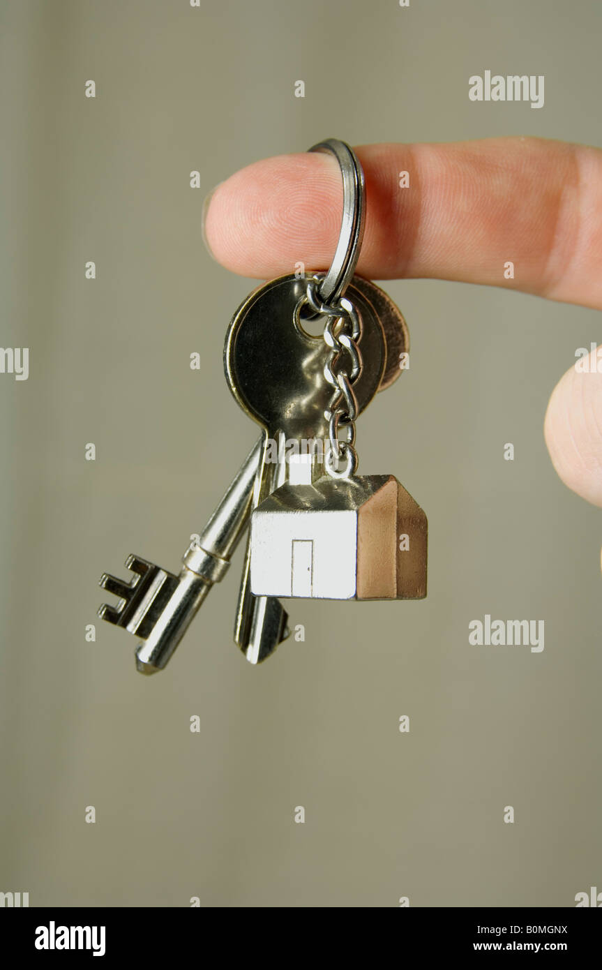A man's hand holding house keys with a house fob Stock Photo - Alamy